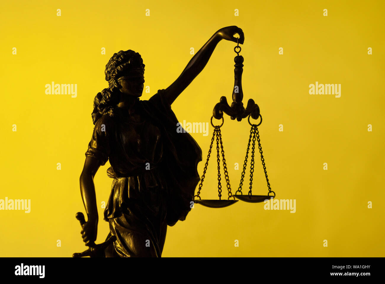 Figure of Justice holding scales over a yellow background with copy ...