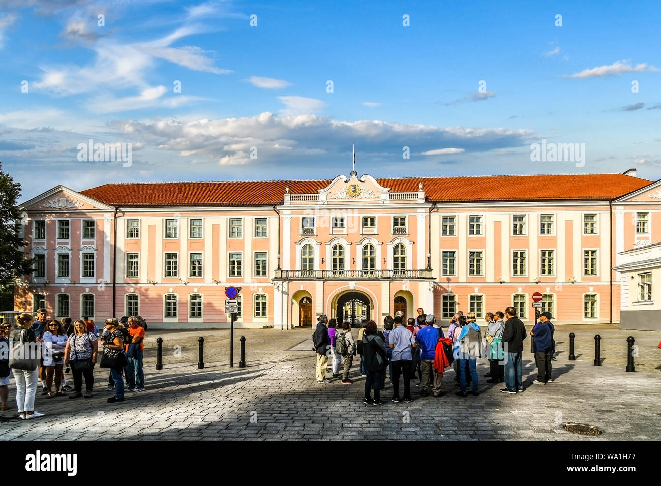 Two tour groups visit the exterior facade of the Tallinn Parliament ...