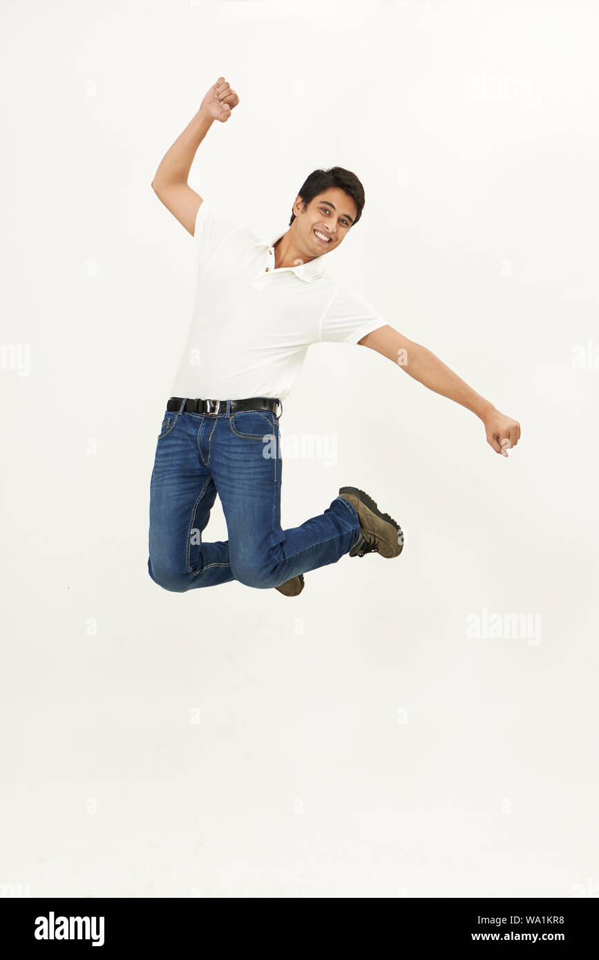 Young man jumping in air and smiling Stock Photo - Alamy