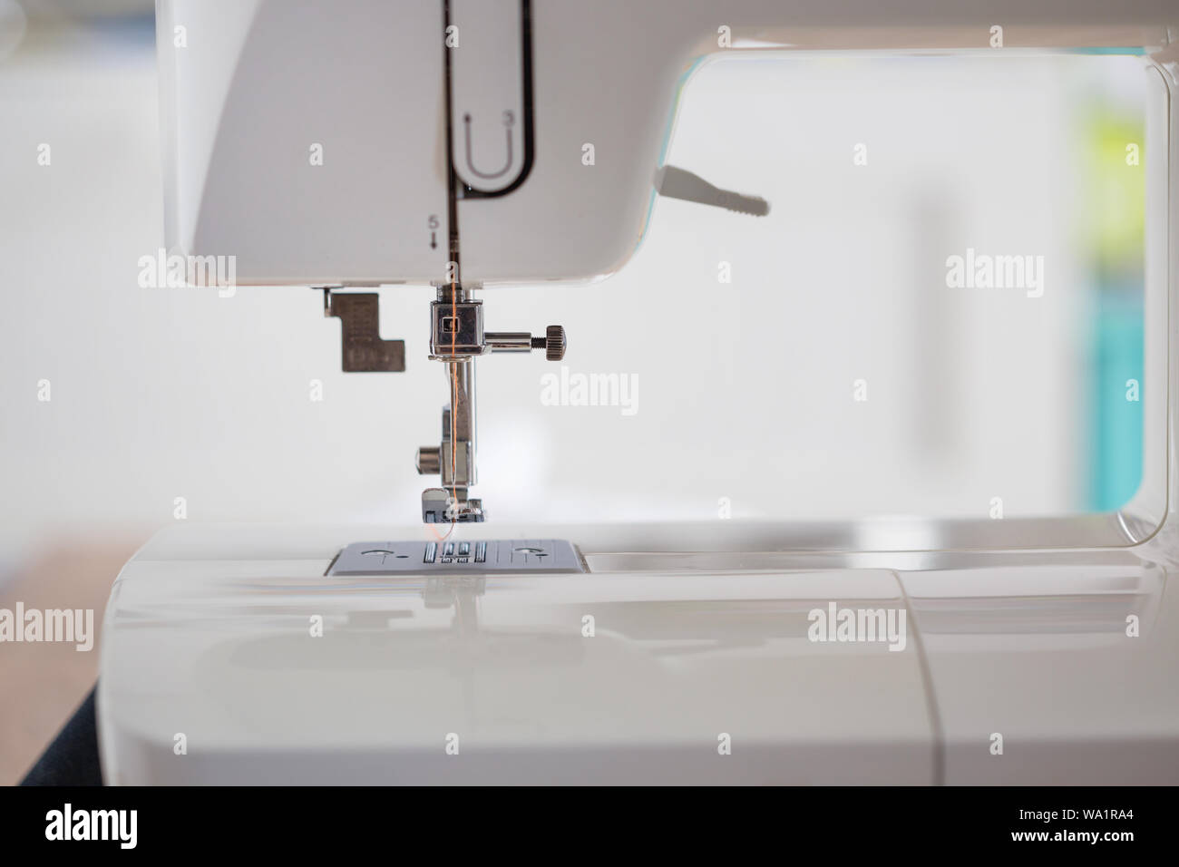 sewing machine with colour thread and needle on a table with blurred ...