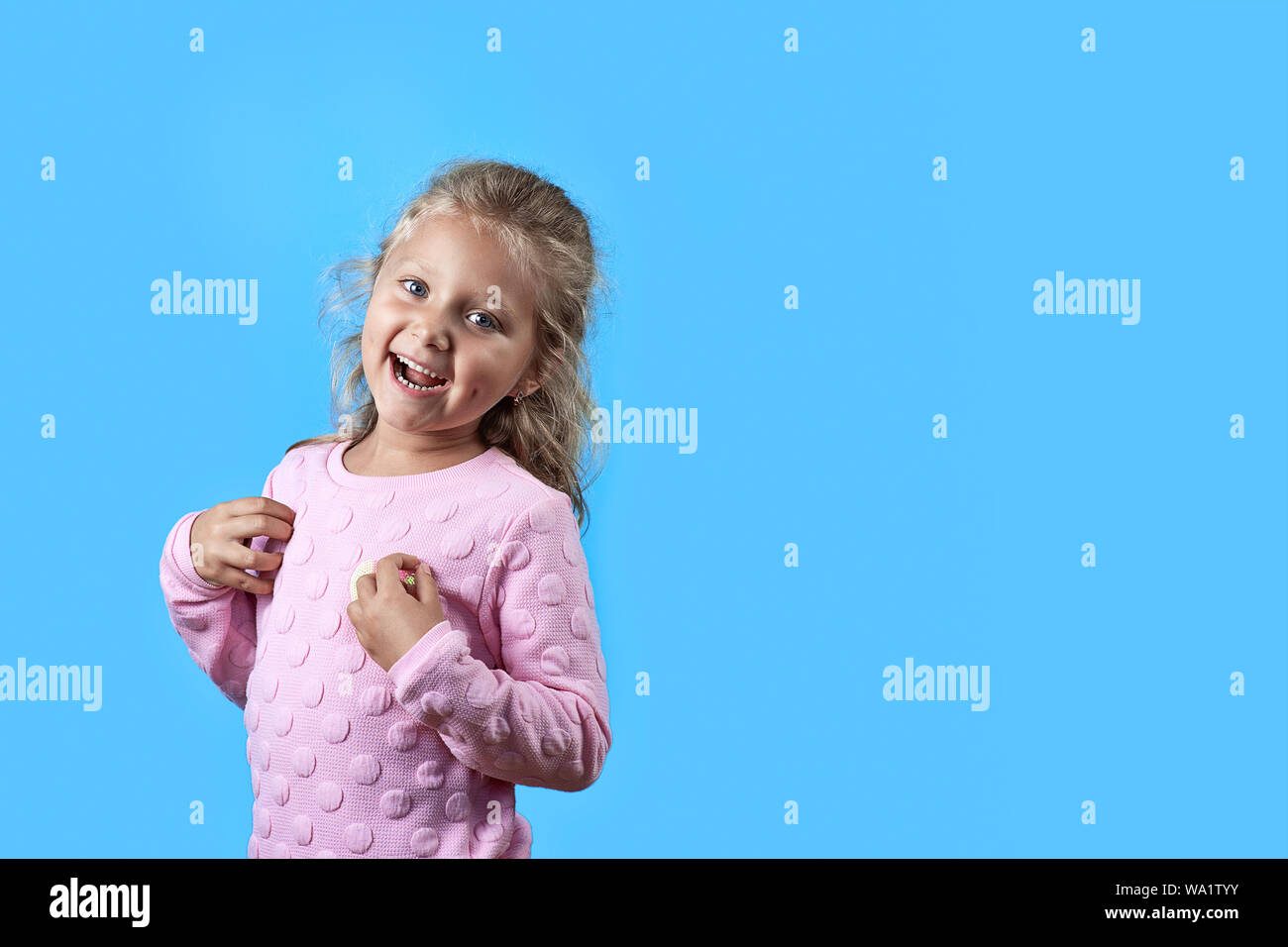 A cute cheerful girl with dimples on her cheeks and curly hair smiles ...
