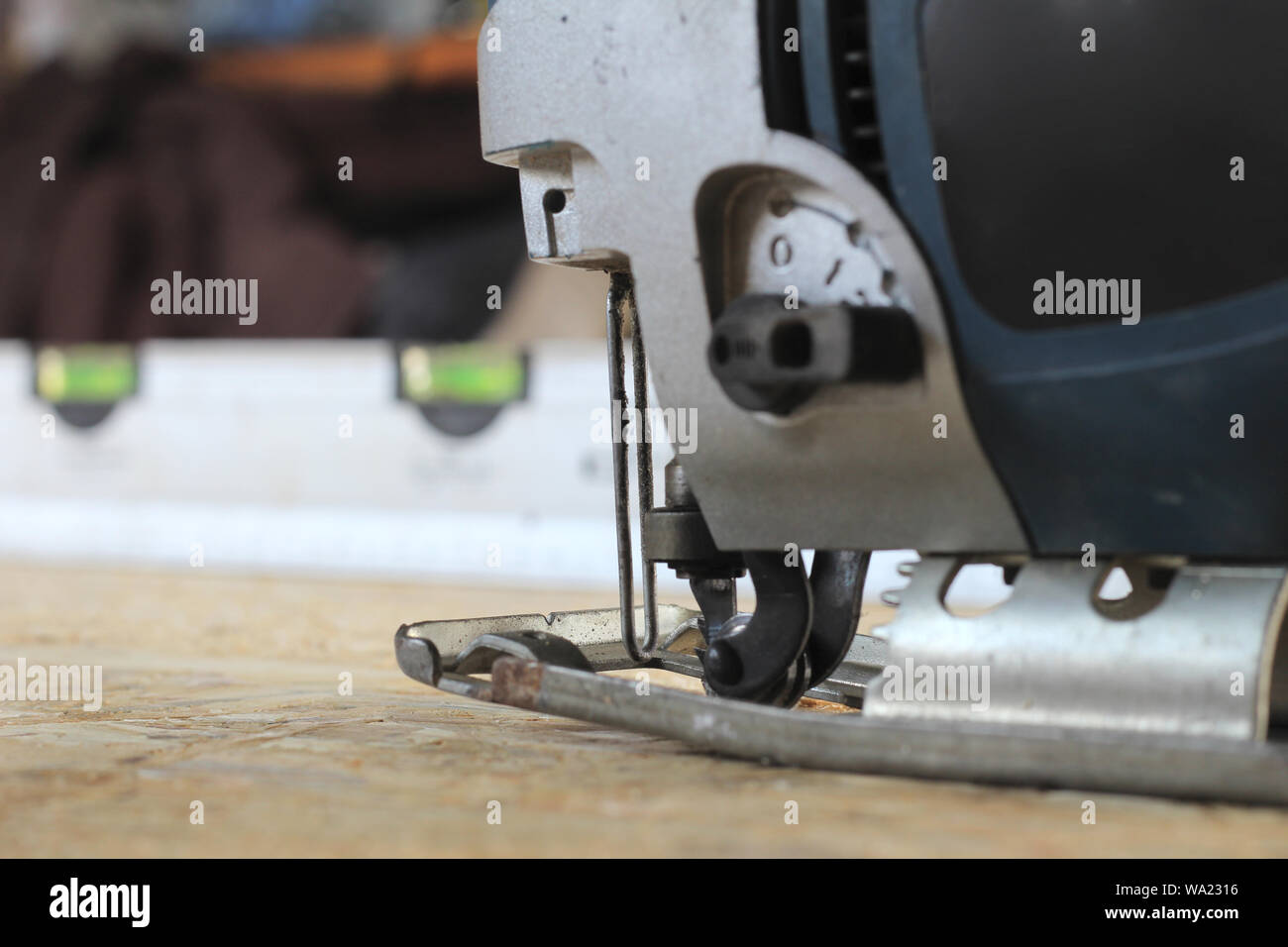 blue-silver electric jigsaw on the osb plate. The process of sawing OSB ...