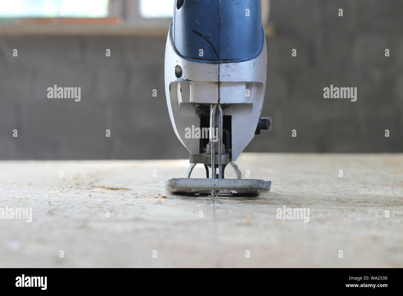 blue-silver electric jigsaw on the osb plate. The process of sawing OSB ...