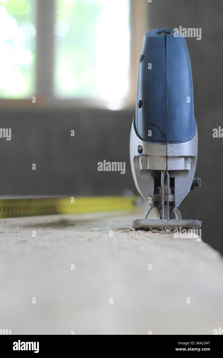 blue-silver electric jigsaw on the osb plate. The process of sawing OSB ...