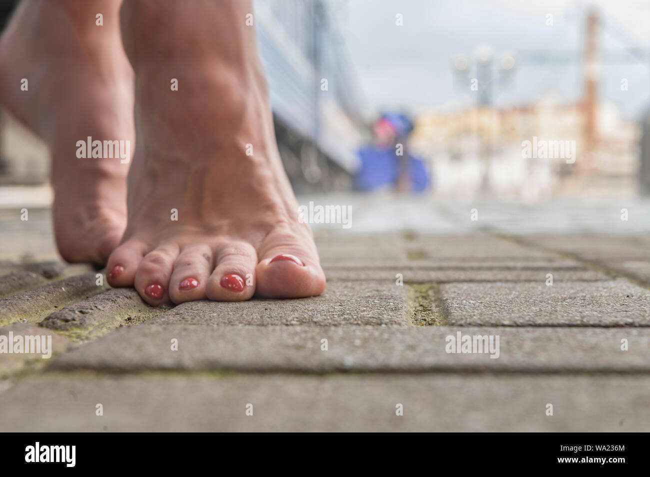 barefoot girl is standing on the railway platform next to the train ...