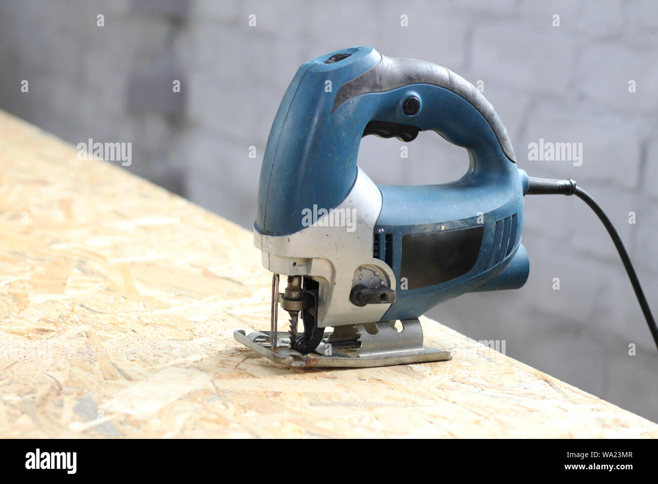 blue-silver electric jigsaw on the osb plate. The process of sawing OSB ...