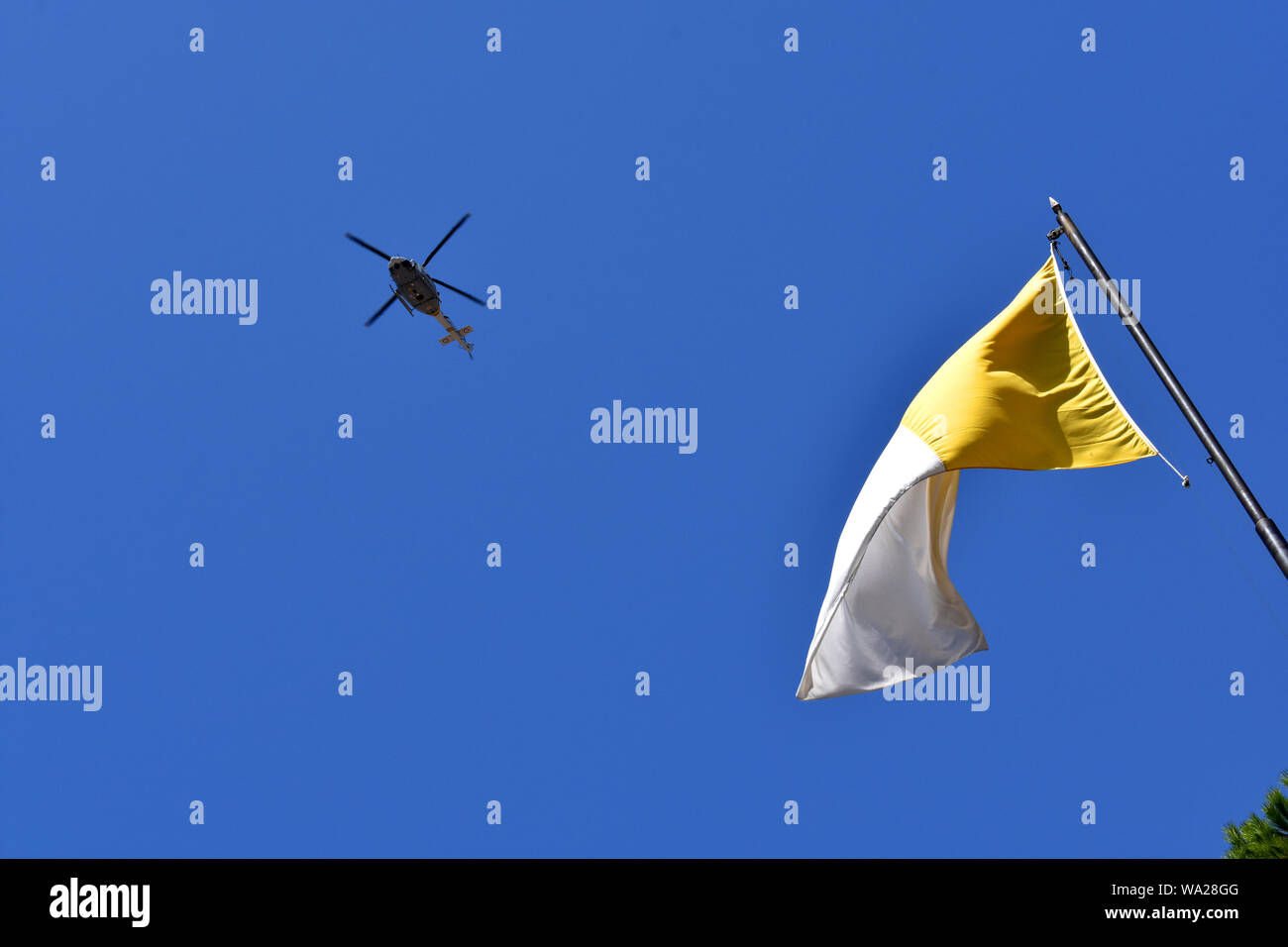Flying helicopter in the blue sky with white and yellow flag waving in ...