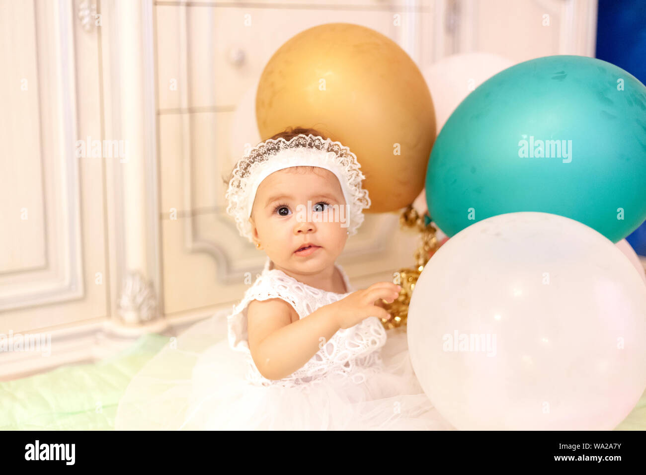 Little princess in white dress playing with air balloons. First ...
