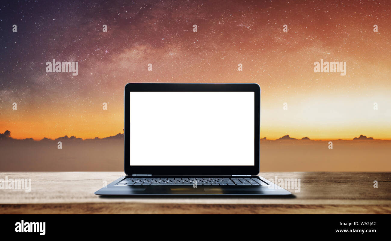 Computer laptop, empty white screen on wooden desk and sunrise sky with ...