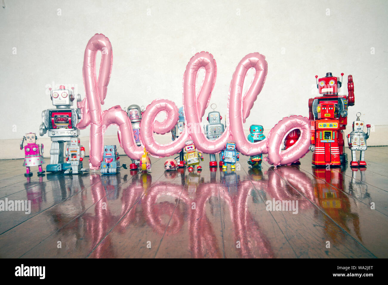 retro robot holding up a pink hello balloon with reflection Stock Photo ...
