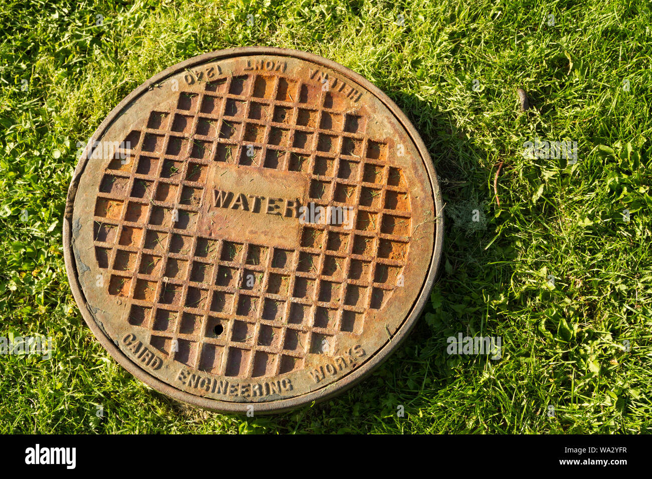 Cast iron water manhole cover surround by grass in a city park in ...