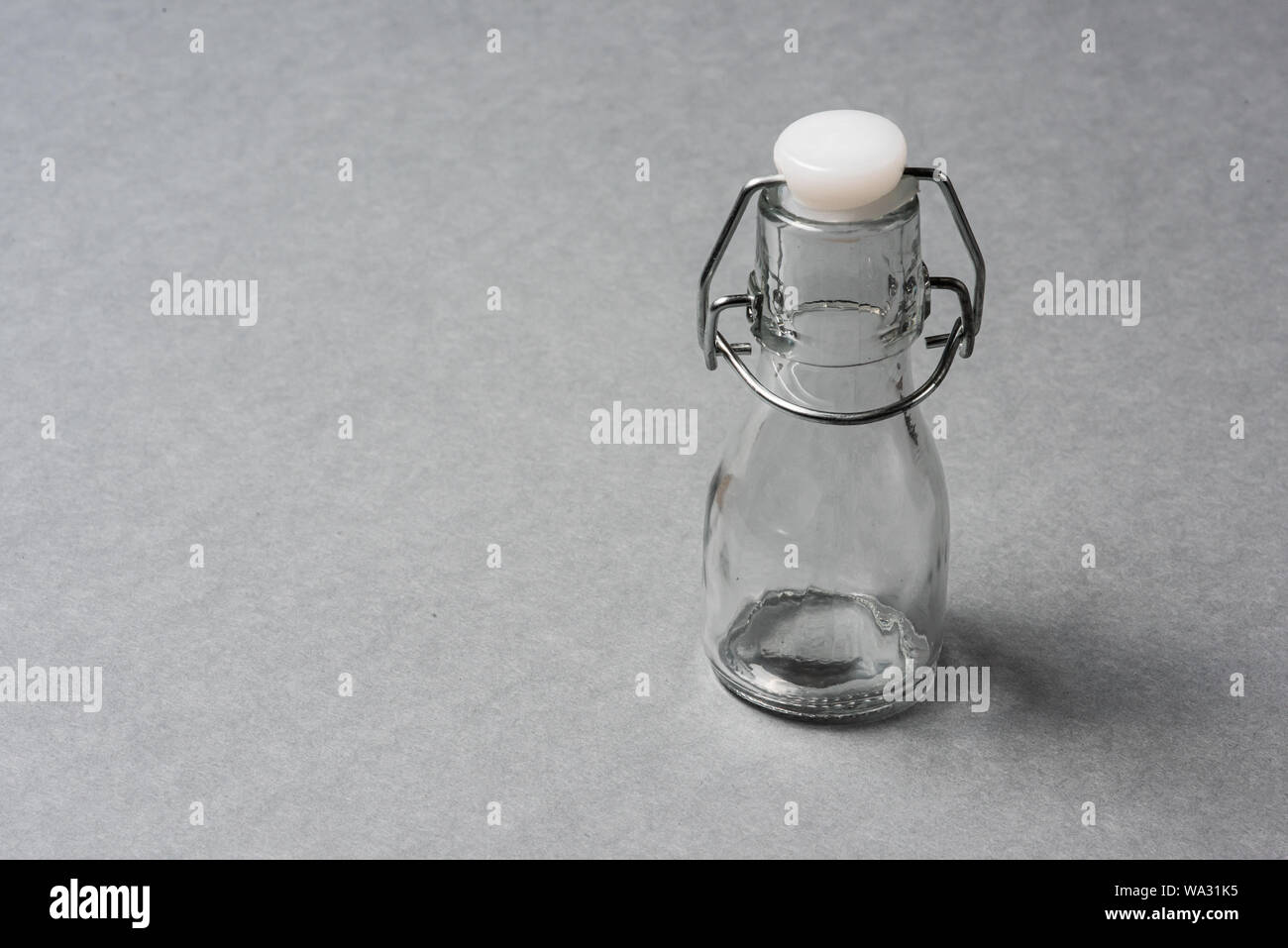 A small glass flask with cap on grey background Stock Photo - Alamy