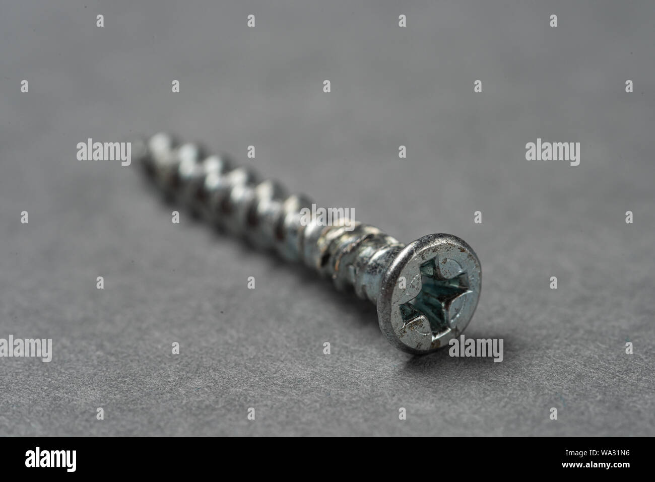 Metal screw on grey background Stock Photo - Alamy