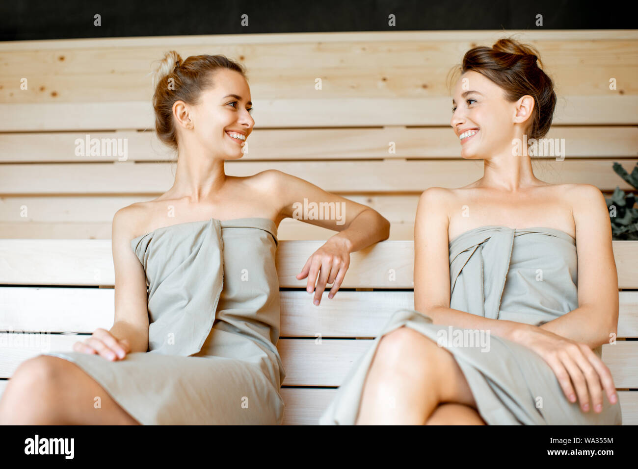 Two young girlfriends having cheerful conversation while relaxing in ...