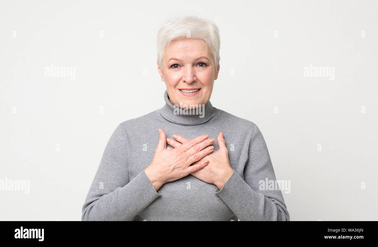 Kind senior woman keeping both palms on chest Stock Photo - Alamy