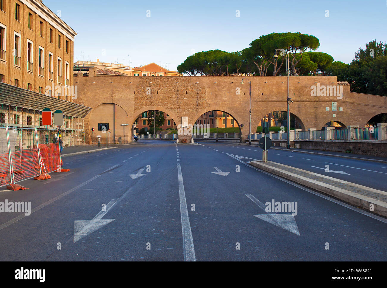Image of a wide empty road with white lines and aroows and street lamps ...