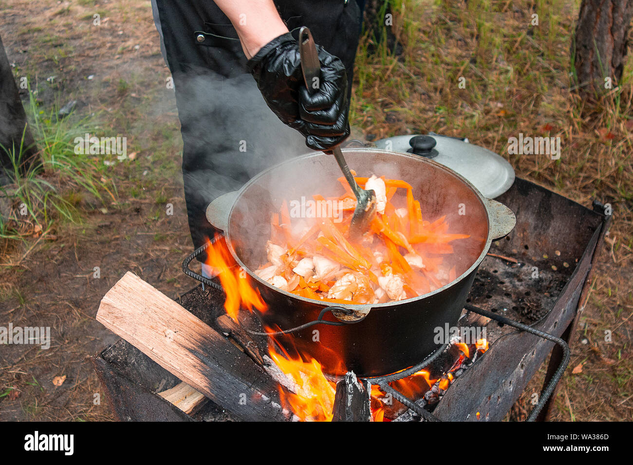 Open air kitchen at party picnic. Pilaf cooking on fire outdoor. Chef ...