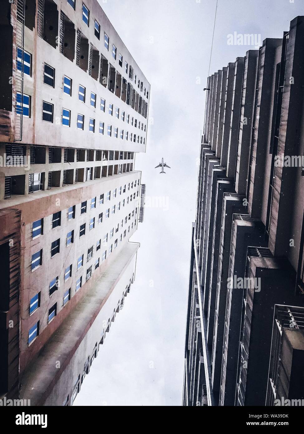 Low angle shot of two apartment buildings with an airplane flying in ...