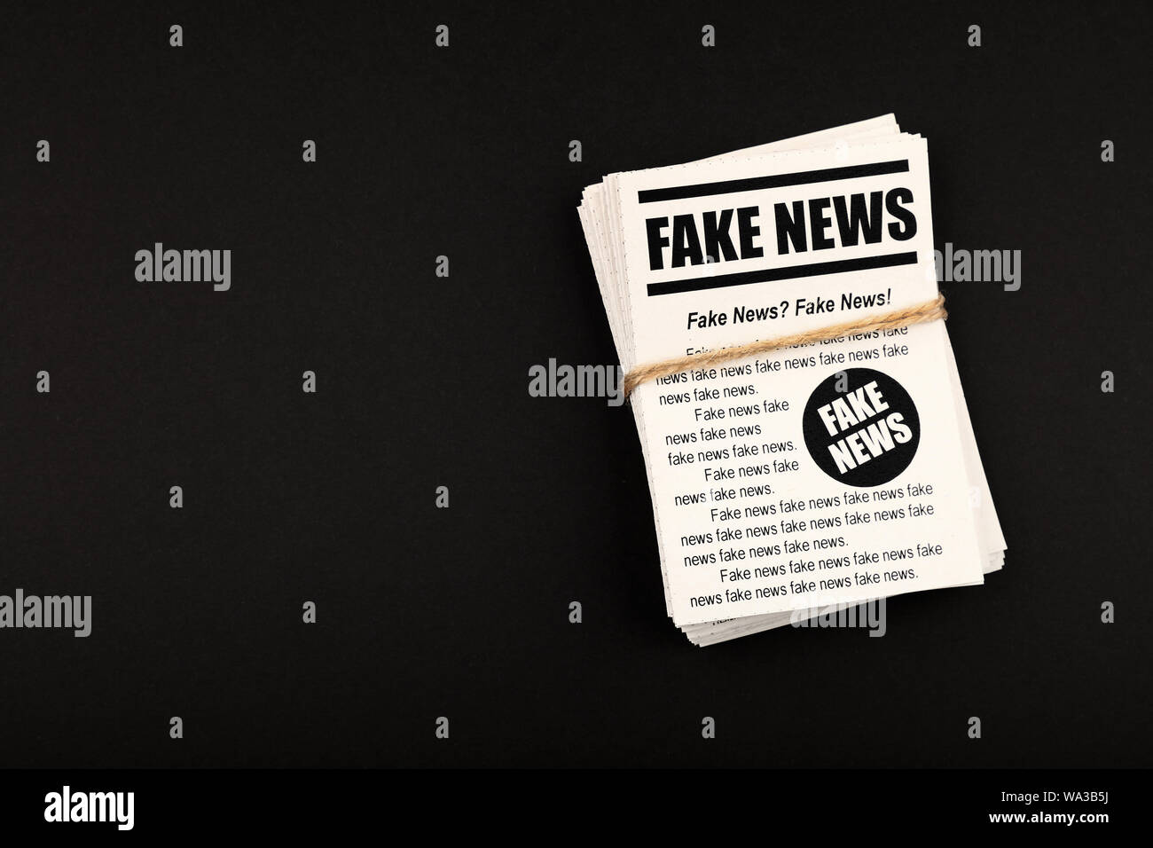 Close up stack of FAKE NEWS newspapers over black paper background with ...