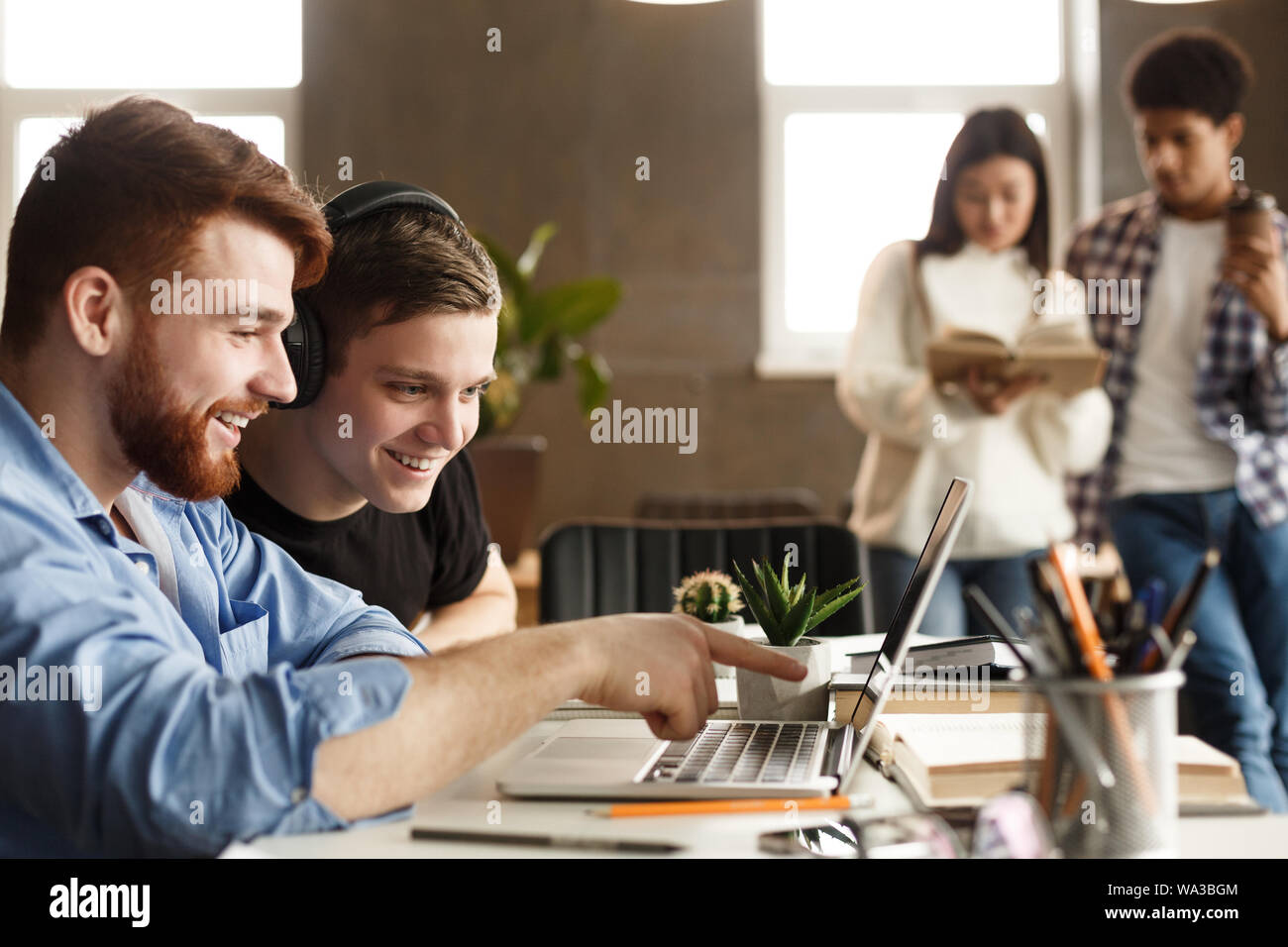 University students at library studying together and connecting online ...