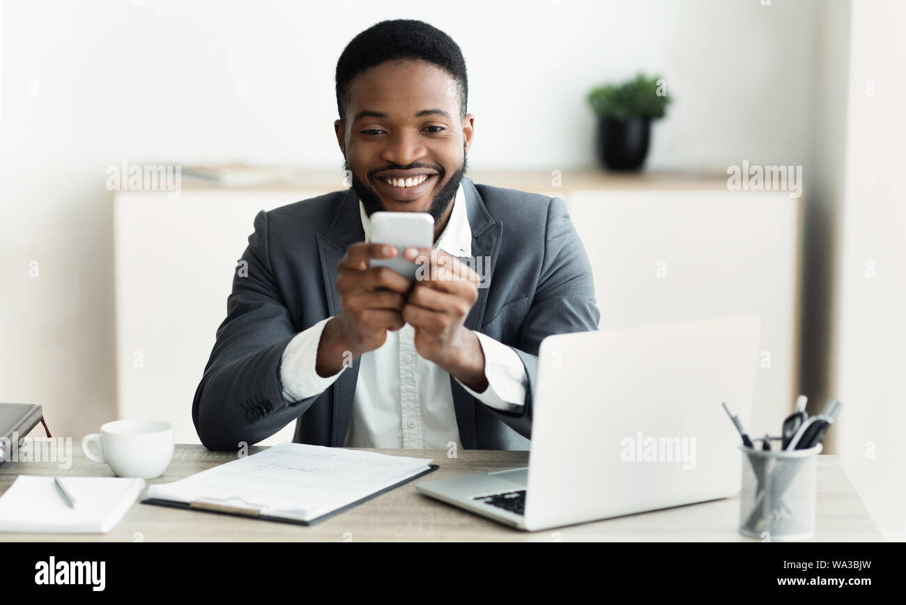 Happy businessman surfing internet on smartphone, working in office ...
