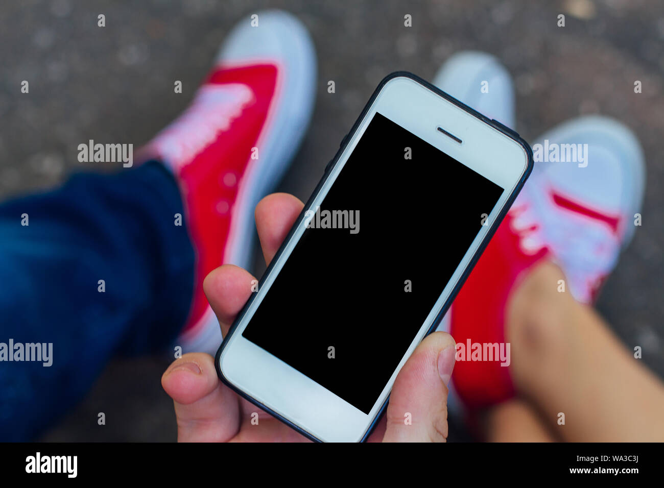 Hand holding mobile phone with blacj screen on background of red ...