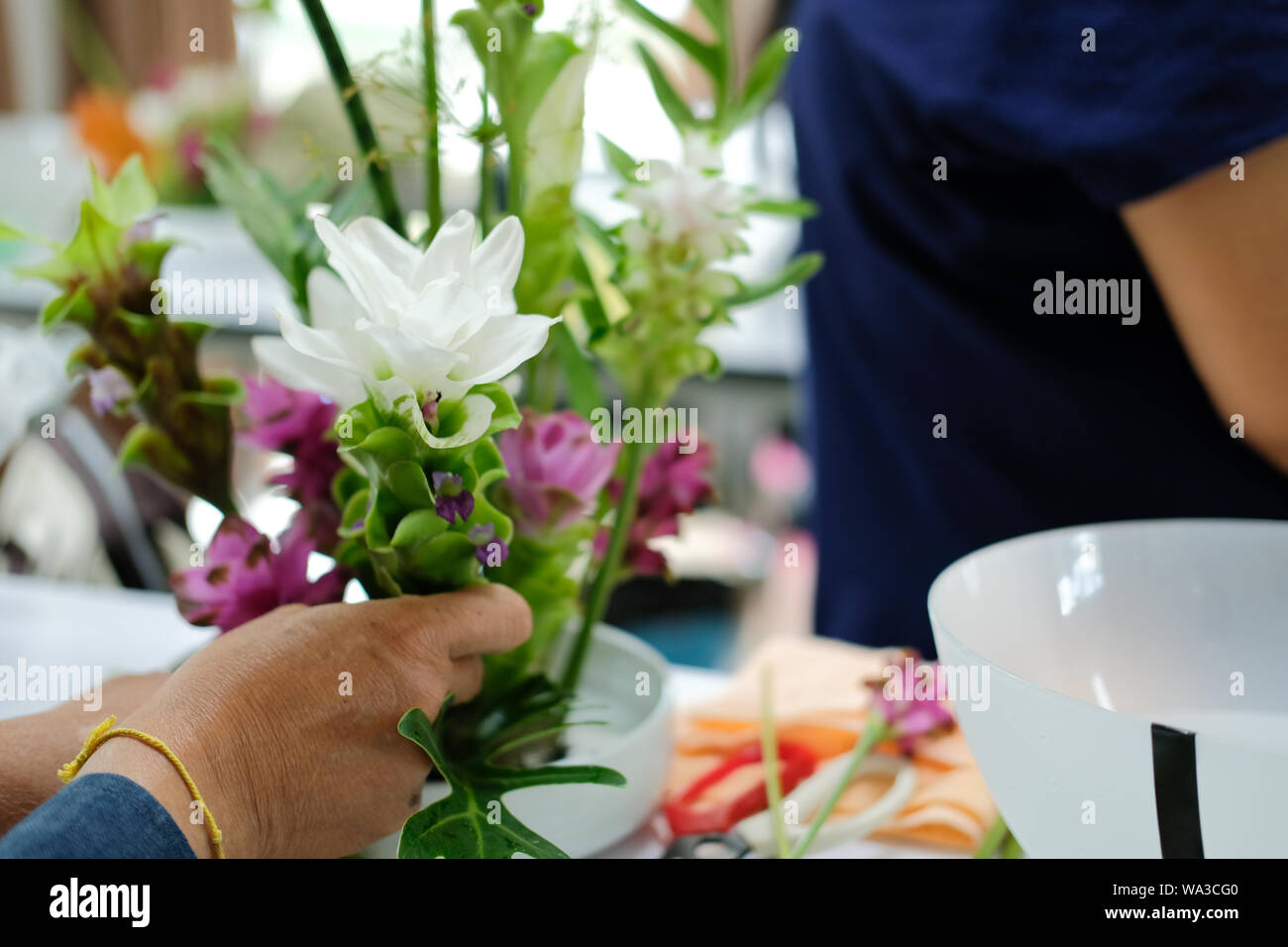 florist arranging flower bouquet in vase. people in floristry class ...