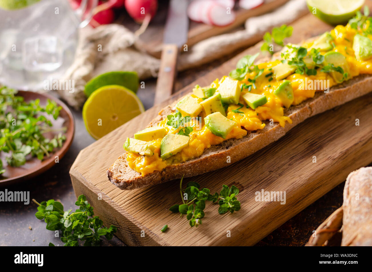 Bio scrambled eggs on rustic french baguette with fresh herbs and ...