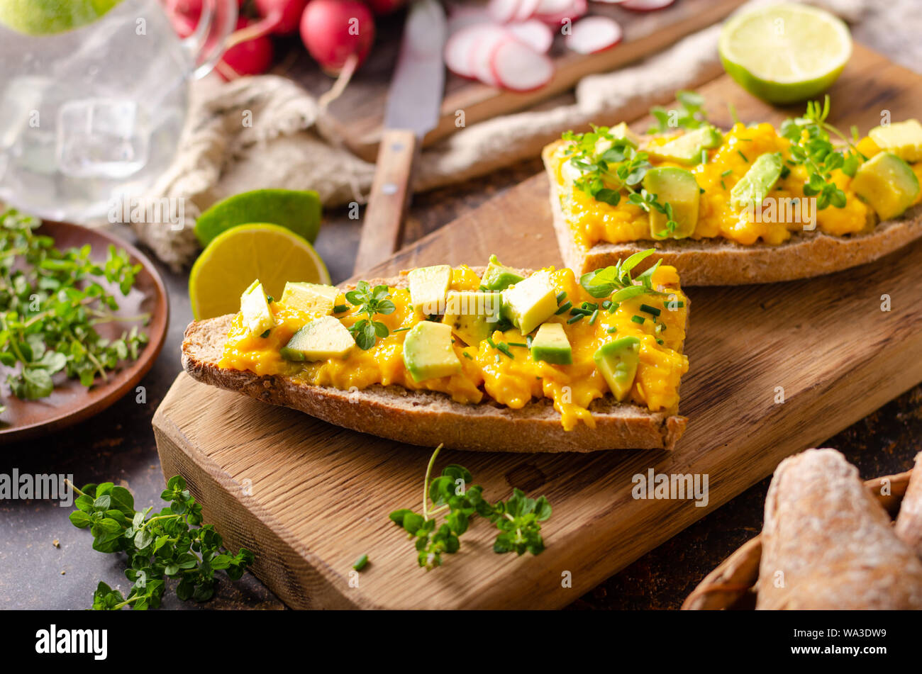 Bio scrambled eggs on rustic french baguette with fresh herbs and ...