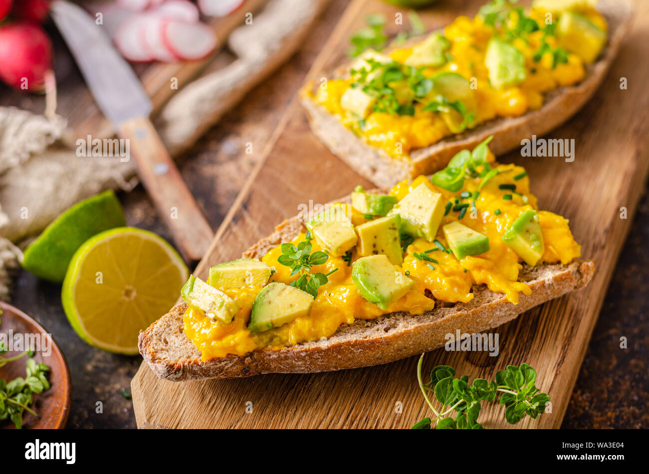 Bio scrambled eggs on rustic french baguette with fresh herbs and ...