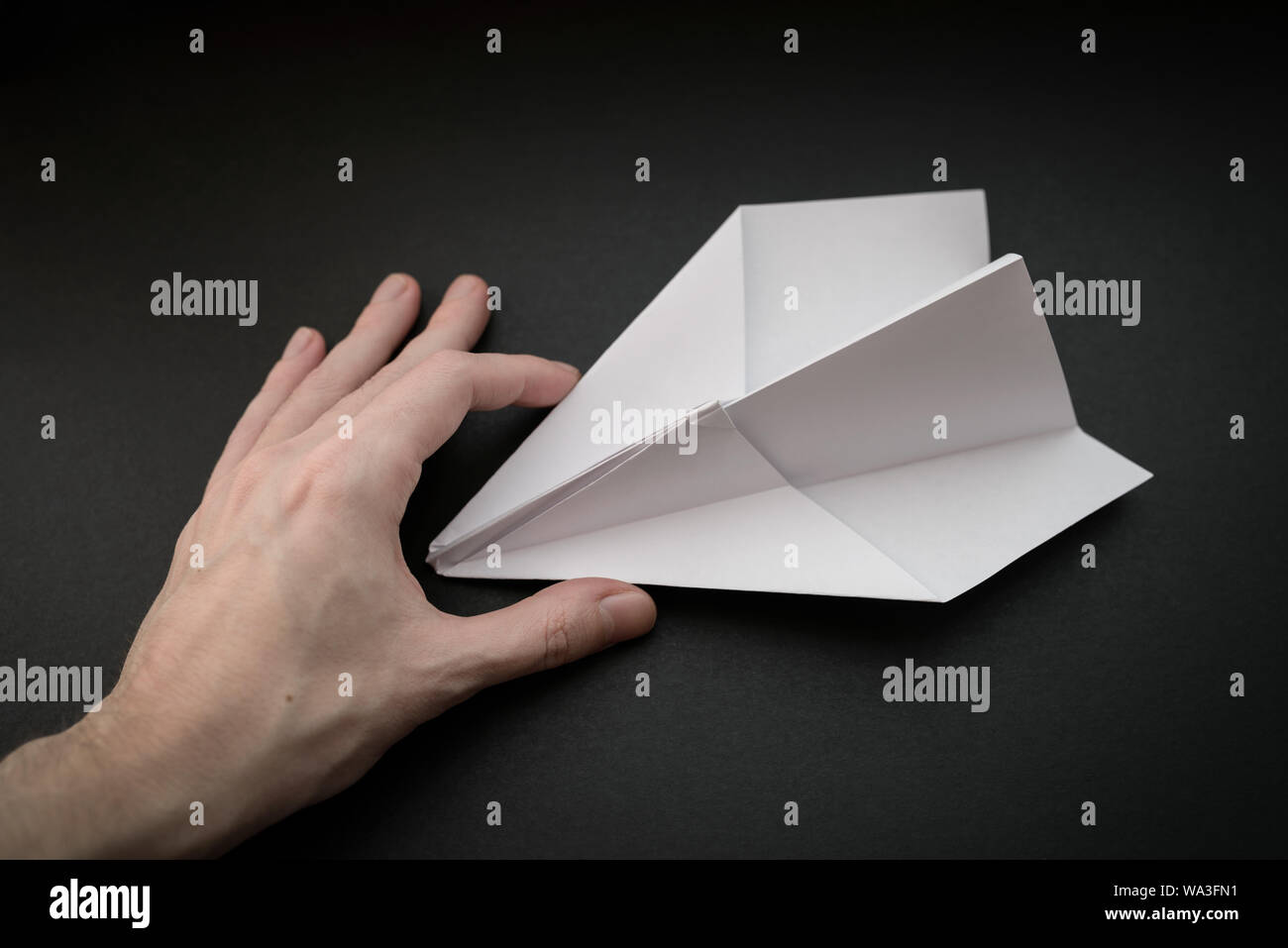 Paper plane in hand on dark background Stock Photo - Alamy
