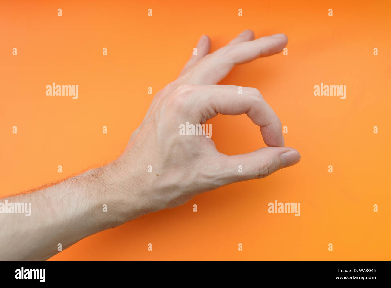 Hand sign ok on orange background Stock Photo - Alamy