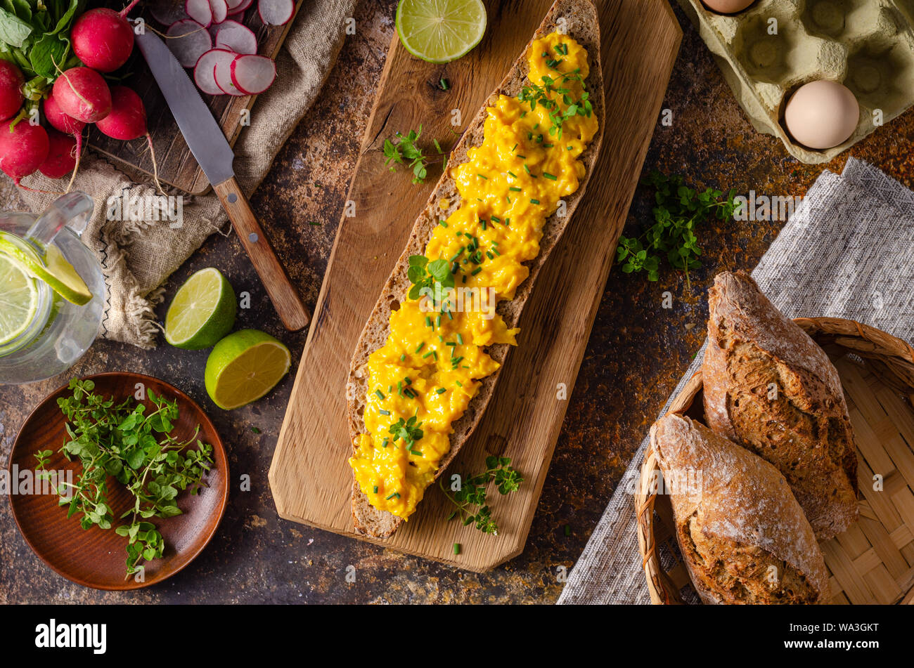 Bio scrambled eggs on rustic french baguette with fresh herbs and ...