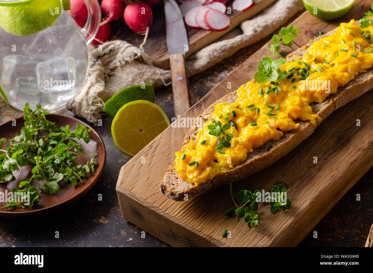 Bio scrambled eggs on rustic french baguette with fresh herbs and ...