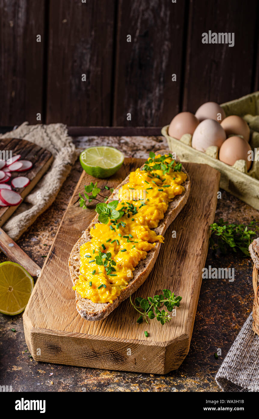 Bio scrambled eggs on rustic french baguette with fresh herbs and ...