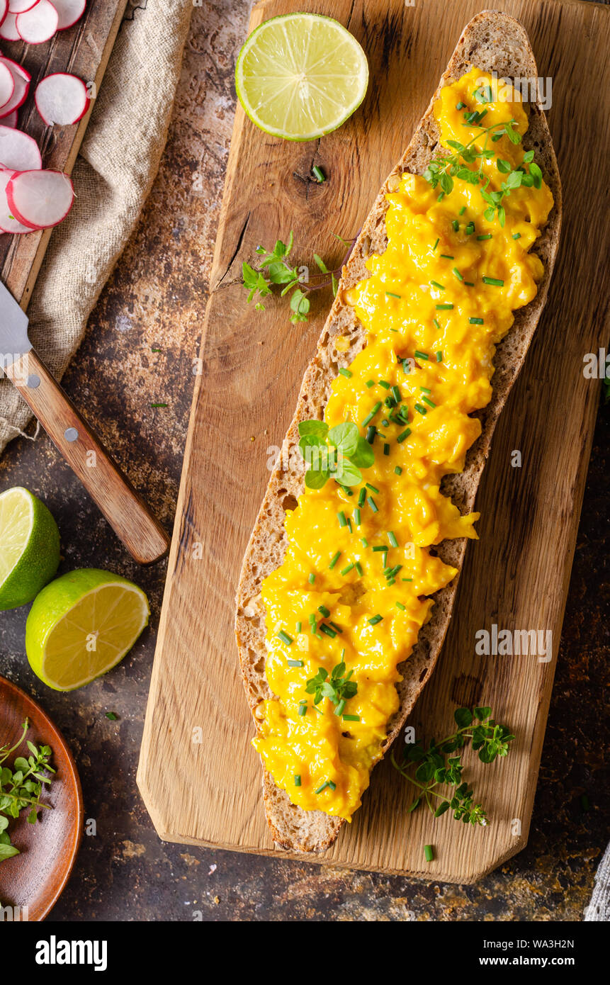 Bio scrambled eggs on rustic french baguette with fresh herbs and ...