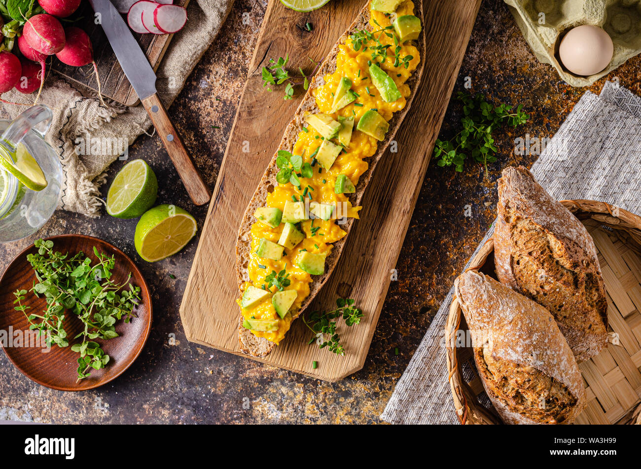 Bio scrambled eggs on rustic french baguette with fresh herbs and ...