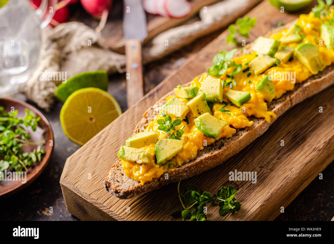 Bio scrambled eggs on rustic french baguette with fresh herbs and ...