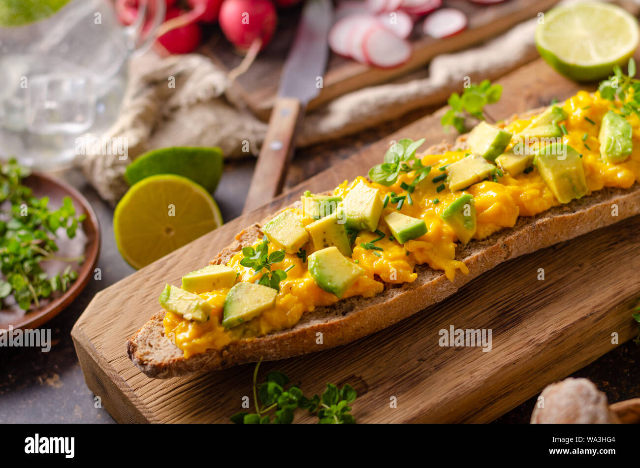 Bio scrambled eggs on rustic french baguette with fresh herbs and ...