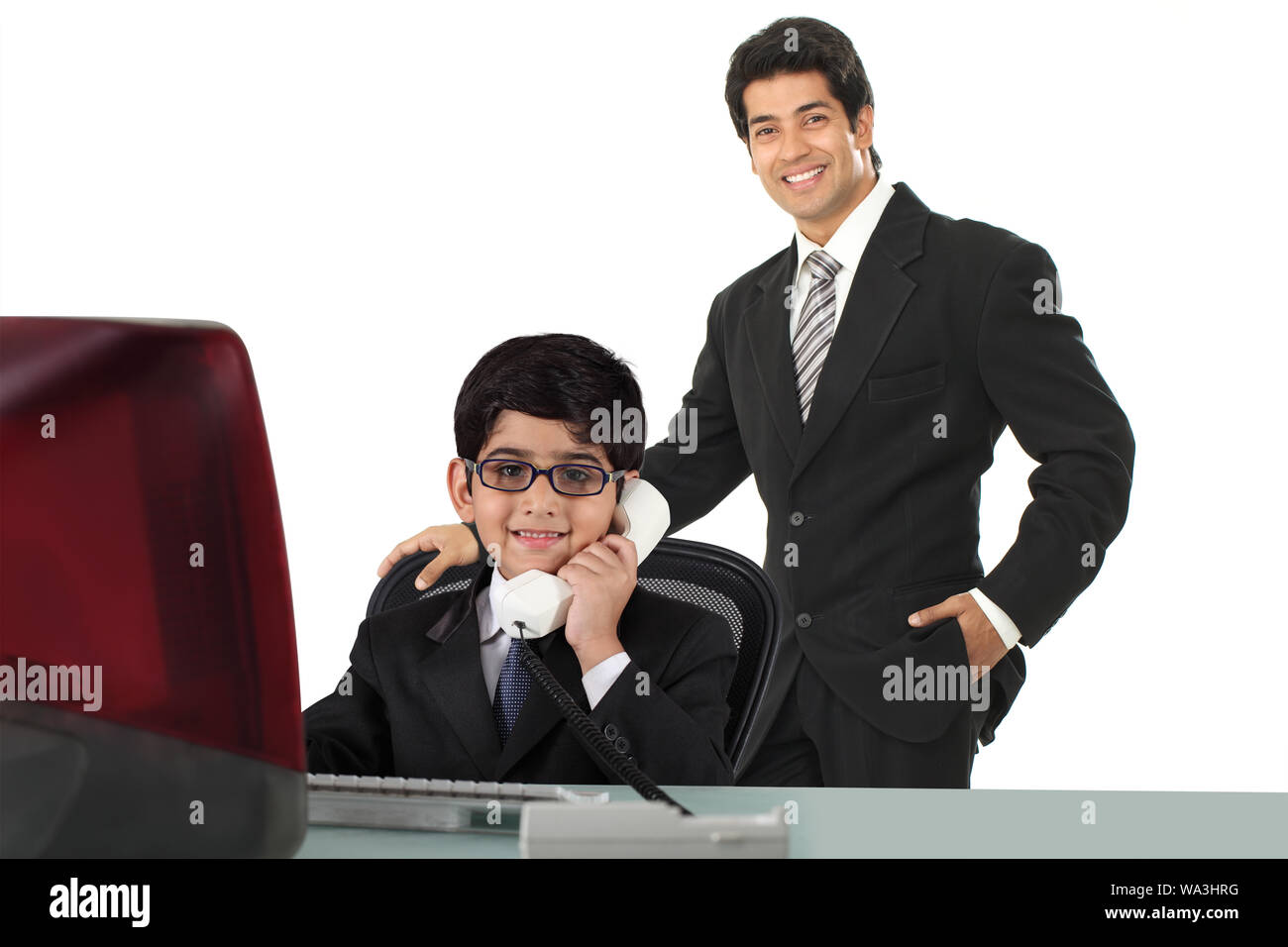 Boy imitating as a businessman and using a computer with his father ...