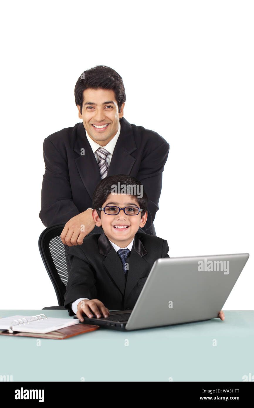 Boy imitating as a businessman and using a laptop with his father Stock ...