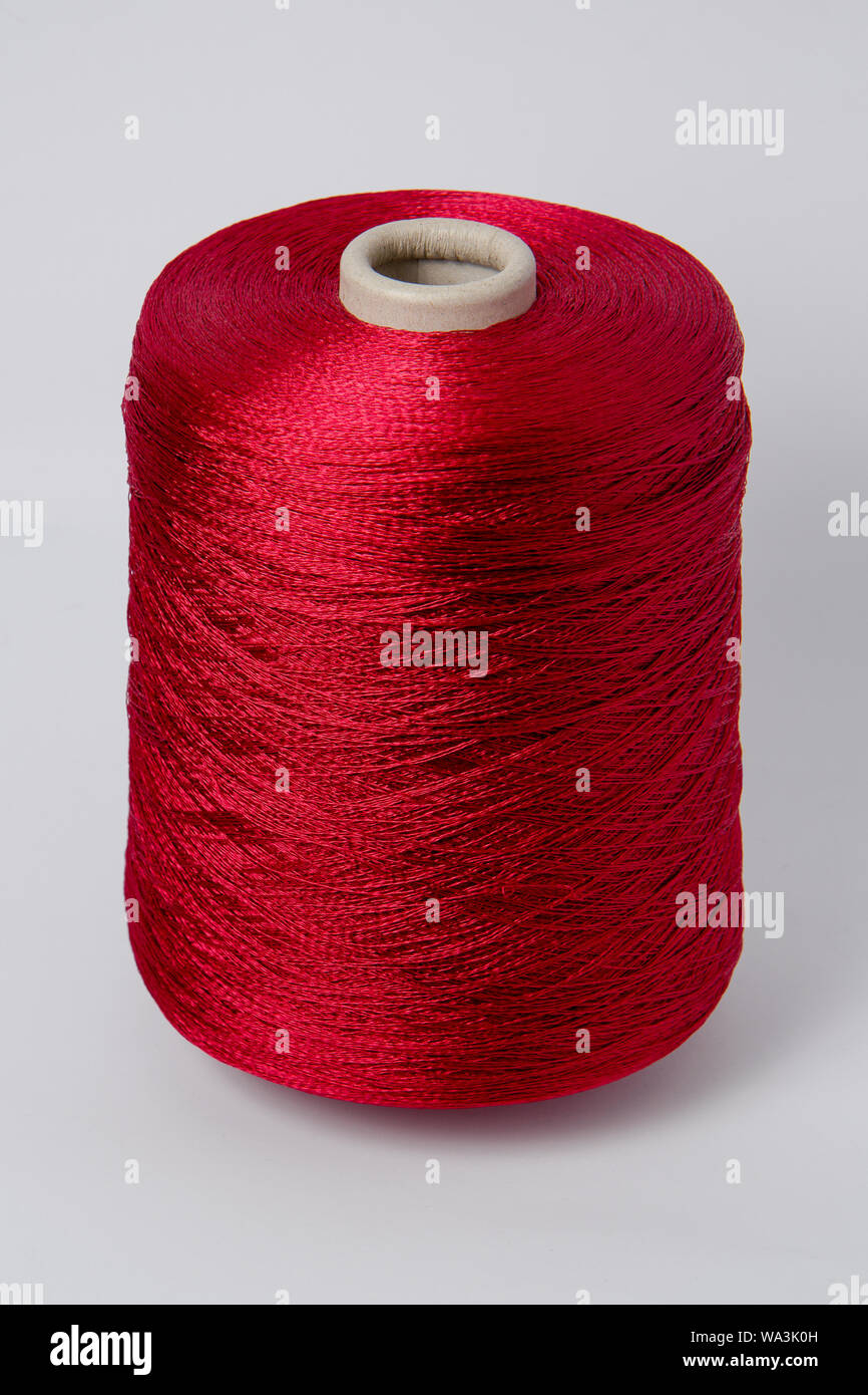Red shiny bobbin of yarn on a white background. Side view.Textile reel ...