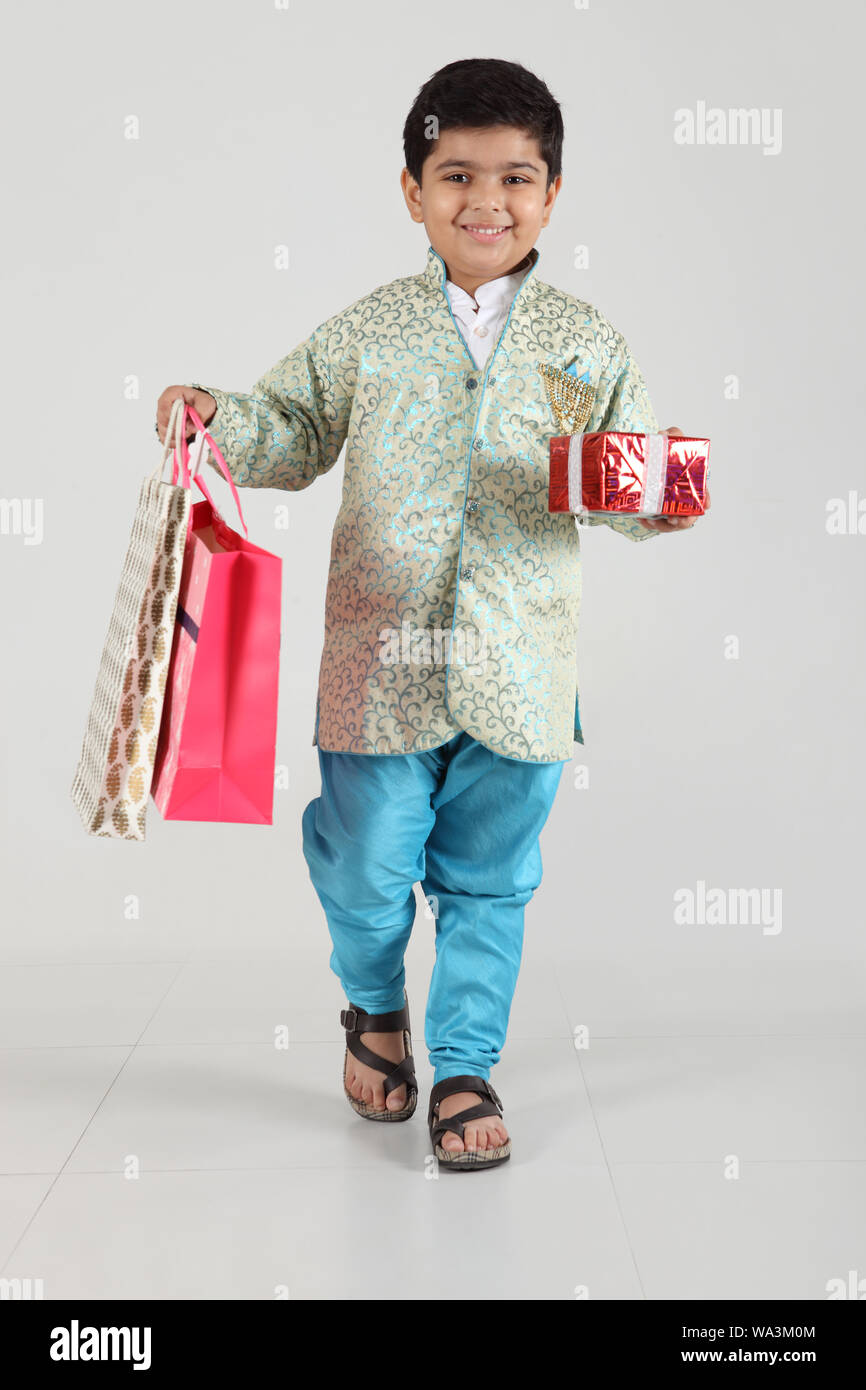 Boy holding a gift box with shopping bags and smiling Stock Photo - Alamy