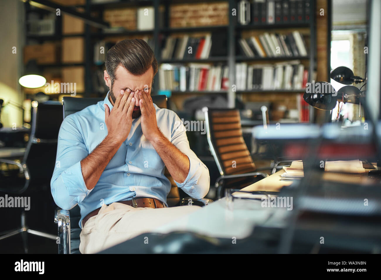 Hard work. Young exhausted bearded businessman covering his eyes and ...