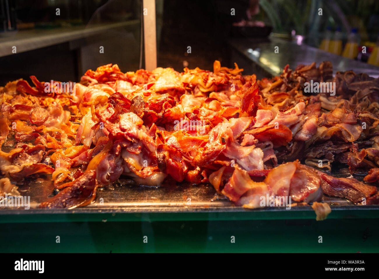 Restaurant window display of heaping pile of bacon under warming lamps ...