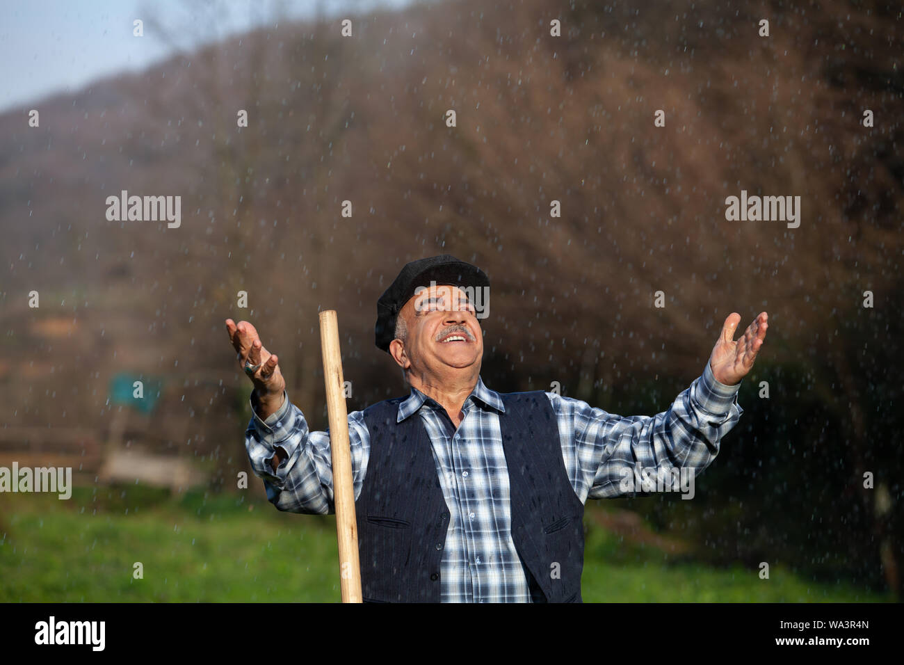 Farmer in the rain ,arms open and happy Stock Photo - Alamy