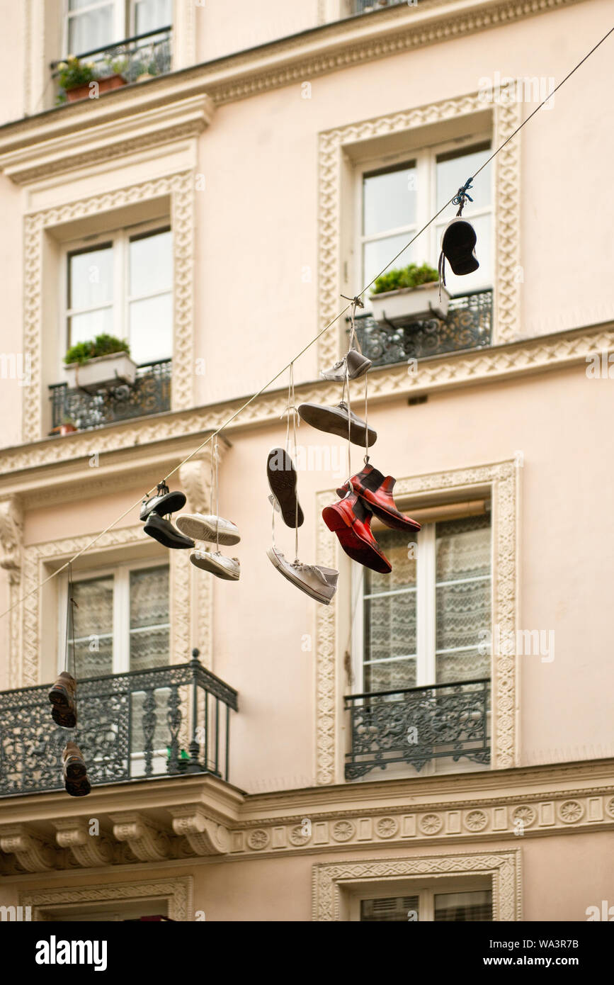 Shows hanging by their shoe laces from line between apartment buildings ...
