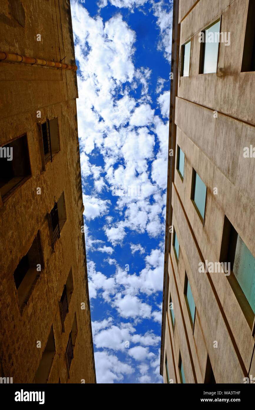 Vertical low angle shot from between two buildings with cloudy sky in the background Stock Photo ...