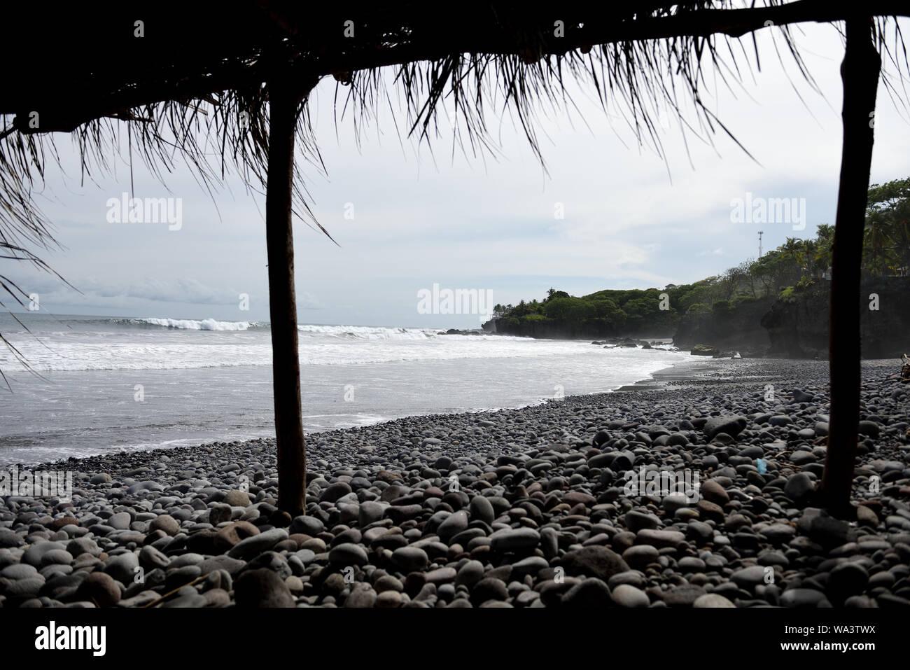 Palapa hut, empty cobblestone beach, Pacific Ocean surf in El Salvador ...