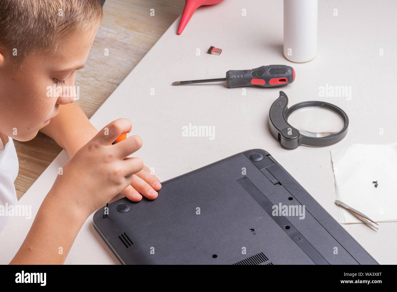 A boy of 10 years old is sorting a laptop for cleaning and maintenance ...